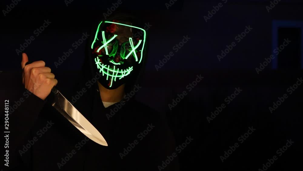 A creepy slasher killer in a generic anonymous halloween horror mask ...