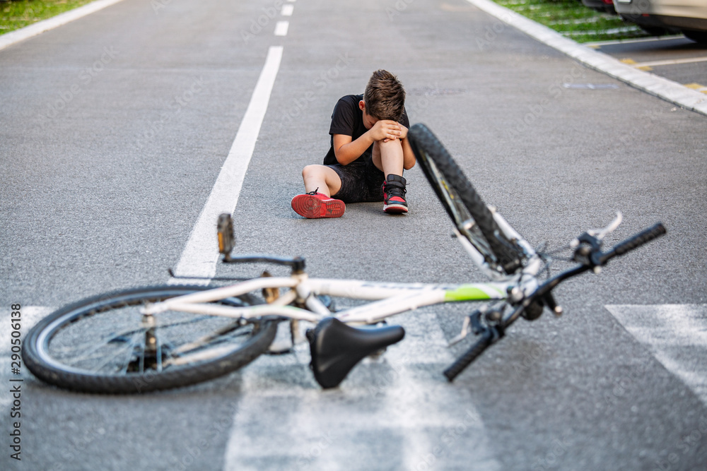 Kid hurts his leg after falling off his bicycle. Child is learning to ...