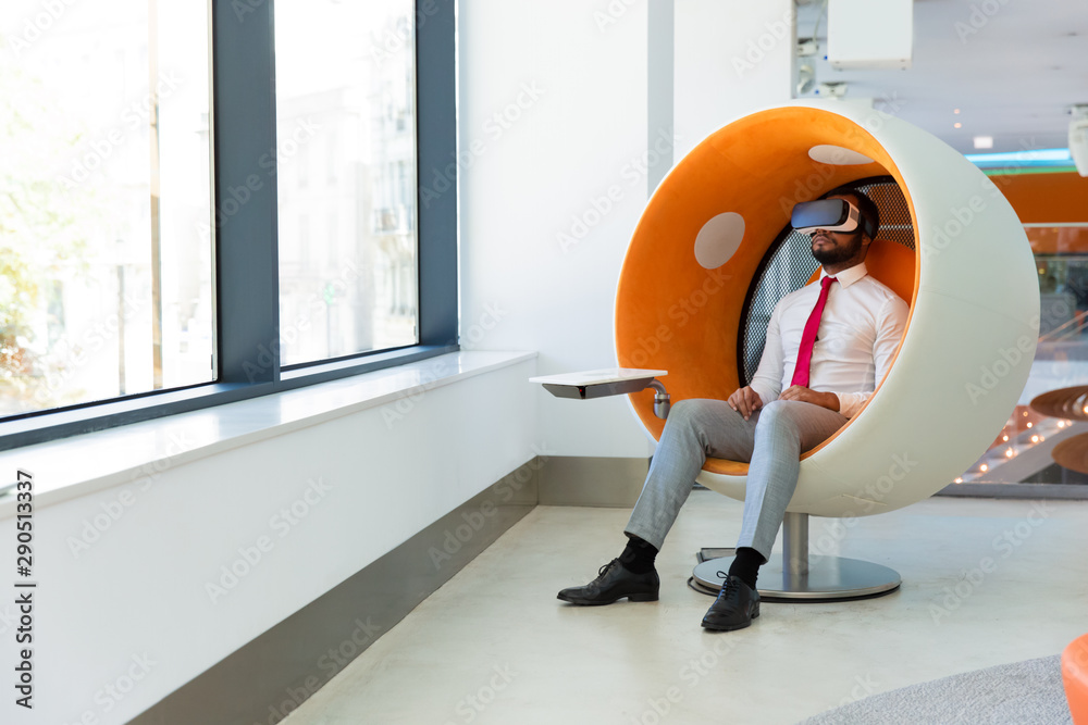 Business leader enjoying VR experience in modern office break area. Man ...