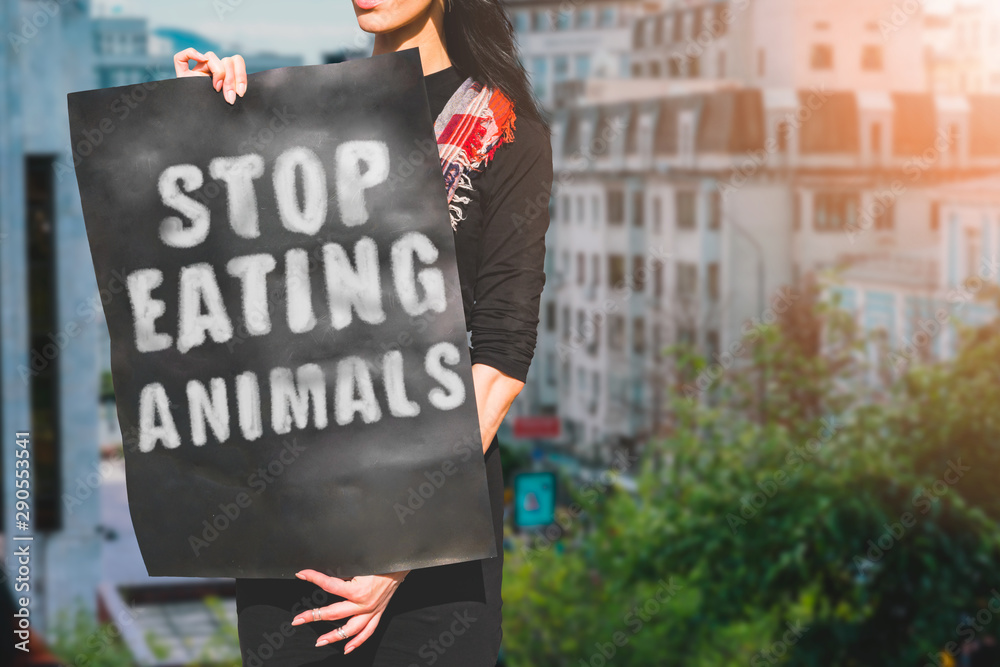 The phrase " Stop eating animals " drawn on a black carton banner in ...