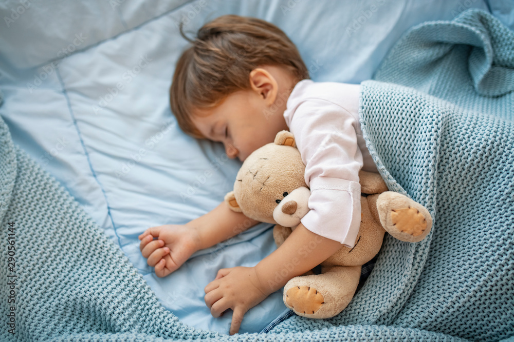 Adorable kid boy after sleeping in grey bed with toy. Cute healthy ...