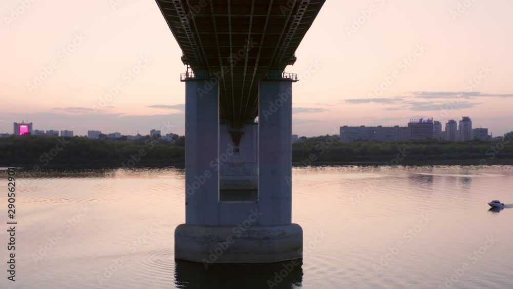 Drone flying between piles under river bridge. Long concrete bridge ...