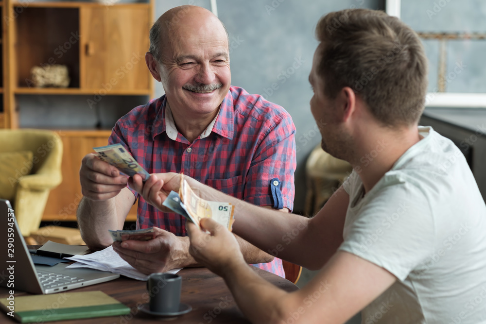 Elderly father lends money to his adult son. He helps his child deal ...