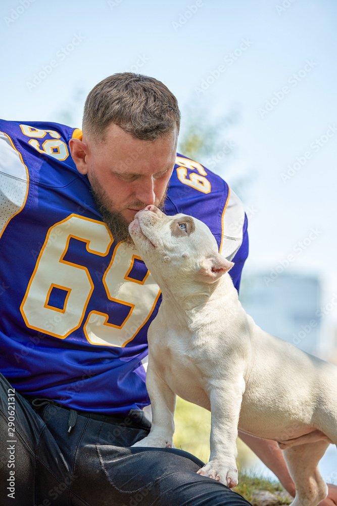 American football player with a dog posing on camera in a park. Copy ...