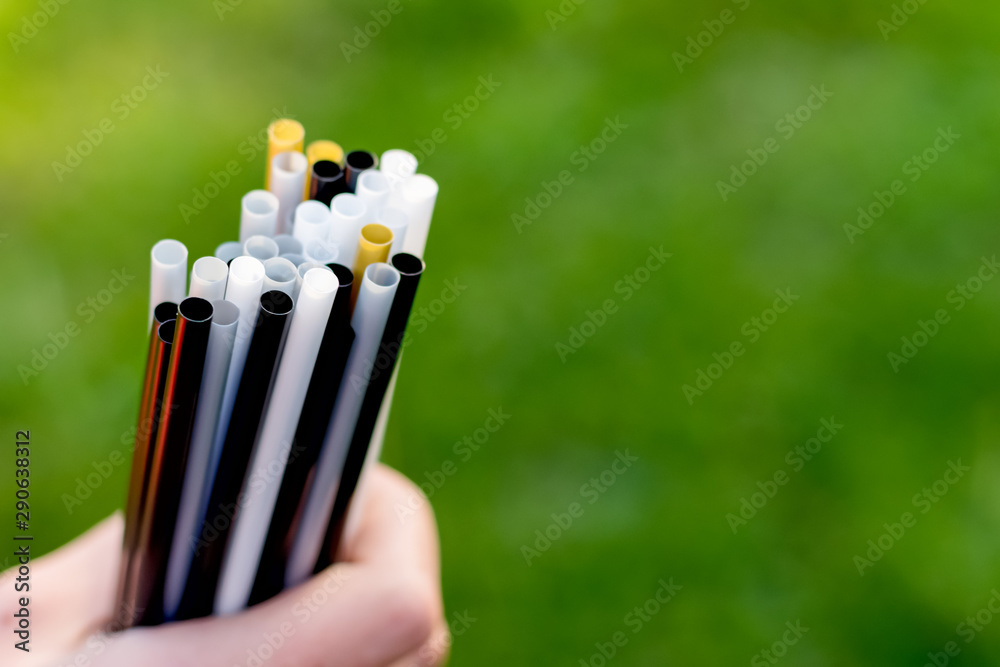Hand holding plastic straws on green grass background. Plastic ...