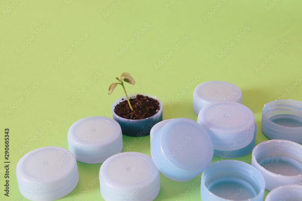 Conceptual photo of a seedling growing out from a plastic bottle cap ...