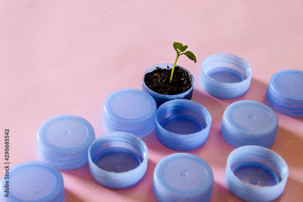 Conceptual photo of a seedling growing out from a plastic bottle cap ...