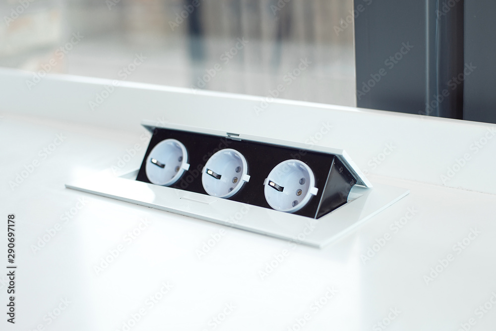 Pop-up internal socket in a white table, charging for phones and ...
