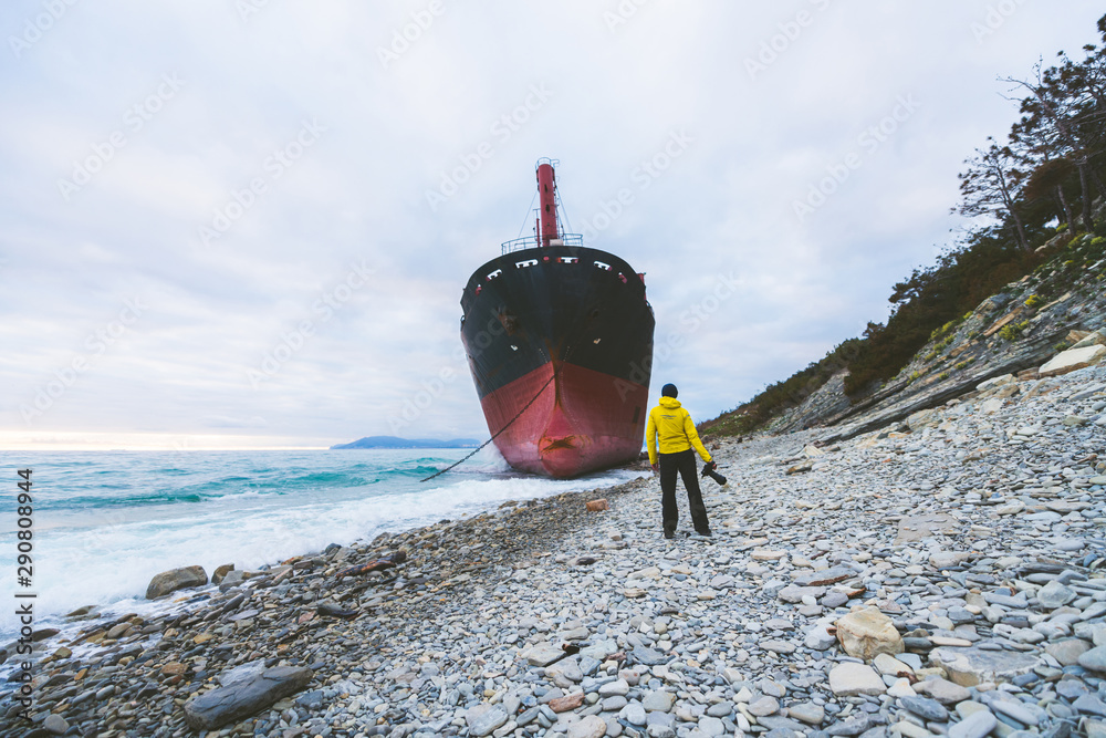 Back view of a traveler man in front of ship aground. Photographer in ...