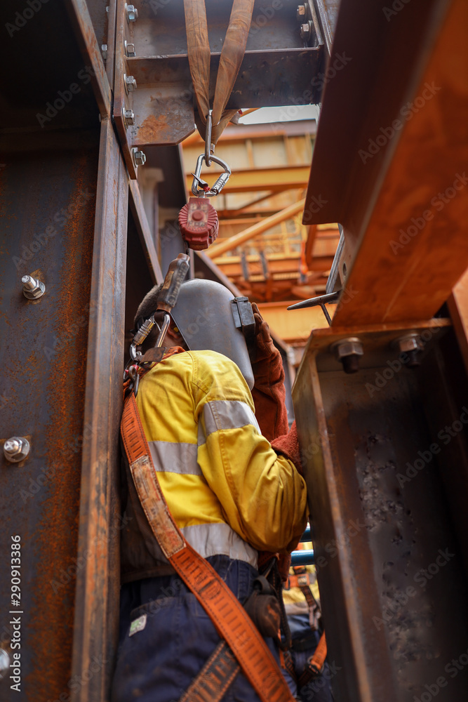 Welder wearing safety helmet, fall arrest construction harness using ...