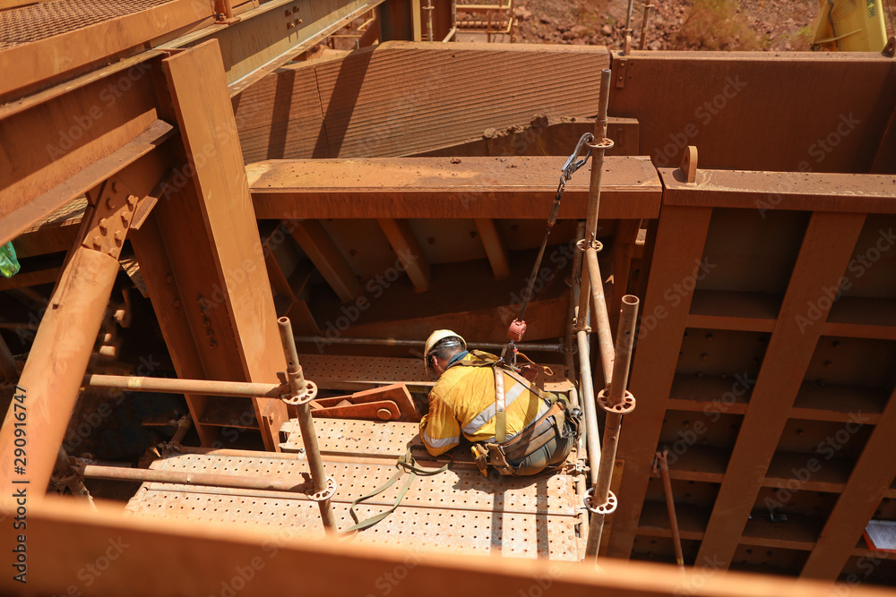 Scaffolder seating wearing safety helmet, fall arrest harness using ...