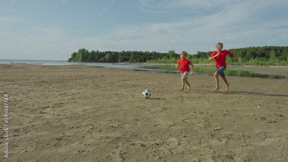 Children playing football at the beach. Slow motion 120 fps. Young boys ...