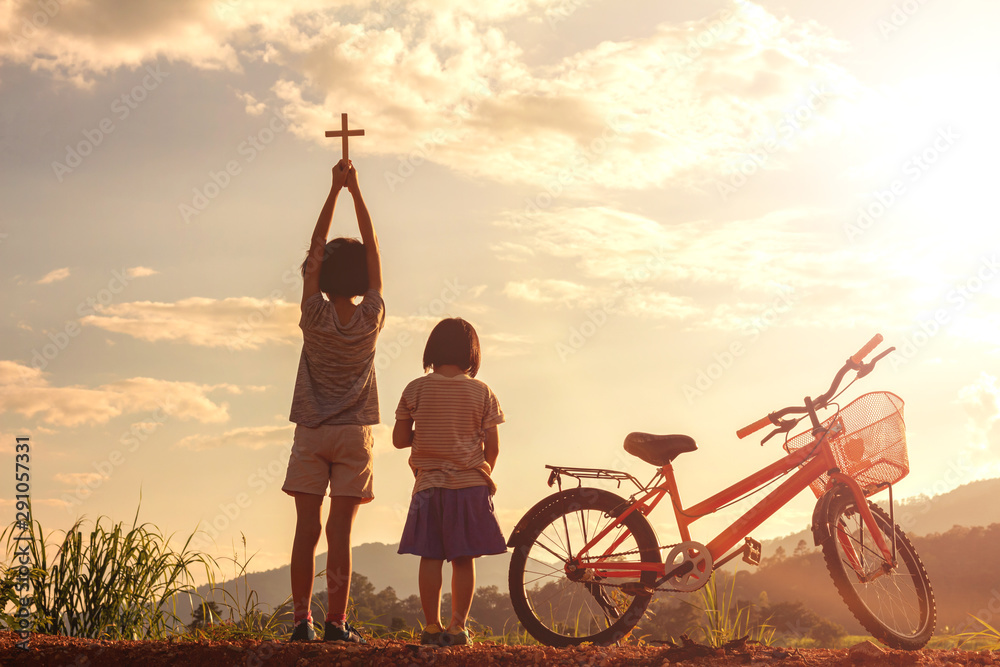 Children standing on mountain praying and holding christian cross for ...