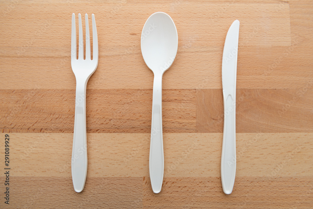 Biodegradable plastic spoon, fork and knife made from starch on wooden ...