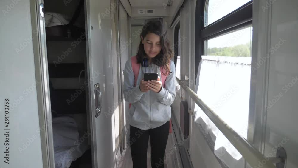 teen girl walks on a train compartment car with a backpack and a ...