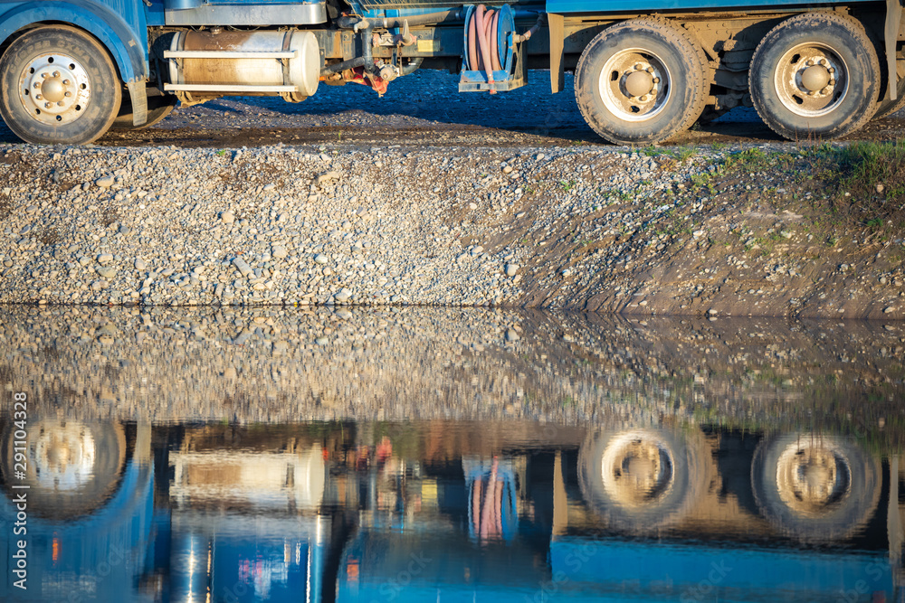 Blue truck parked next to body of water with reflection concept for ...