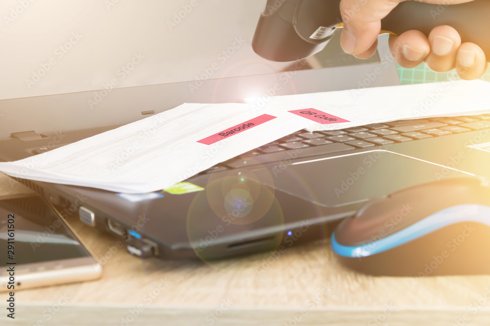 Blurred image hand holding barcode reader focus to barcode on paper ...