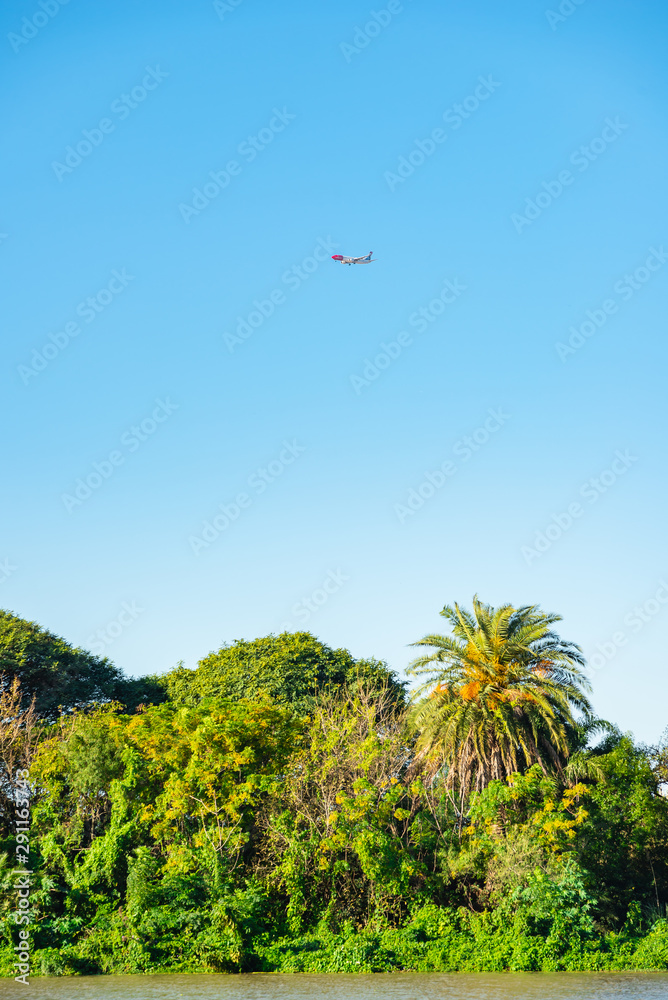 River landscape with trees with a plane flying with the landing gear ...
