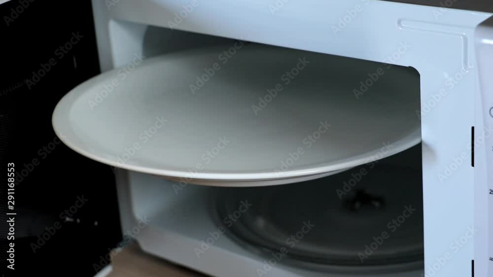The open microwave with a white plate. An empty large disc is wedged in ...