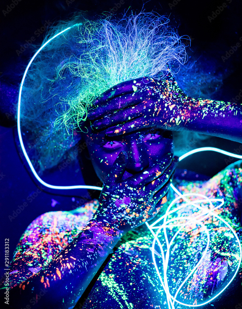Body art and contact lenses glowing in ultraviolet light. Portrait of a ...
