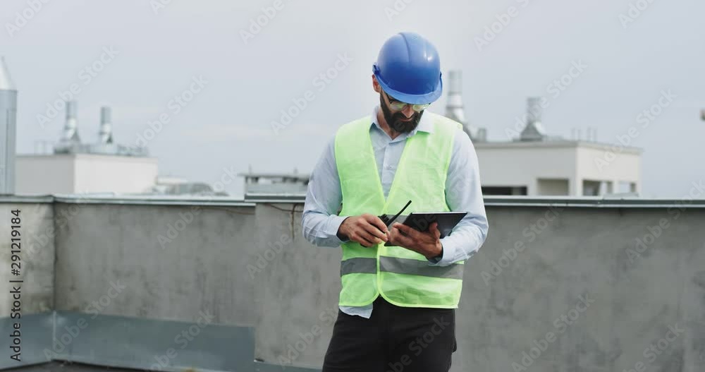 Concentrated engineer with a beard analyzing the construction plan of ...