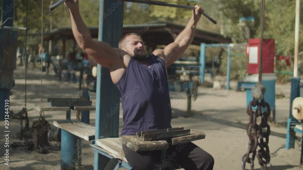 Handsome male bodybuilder doing strength training exercise using cable ...