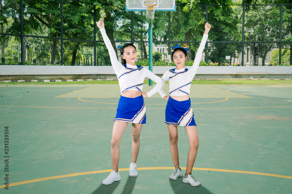 Two high school cheerleaders cheer on basketball field Stock Photo ...