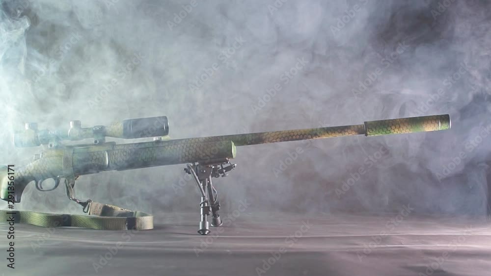 Slow plan of sniper rifle with silencer. Dark background and overhead ...