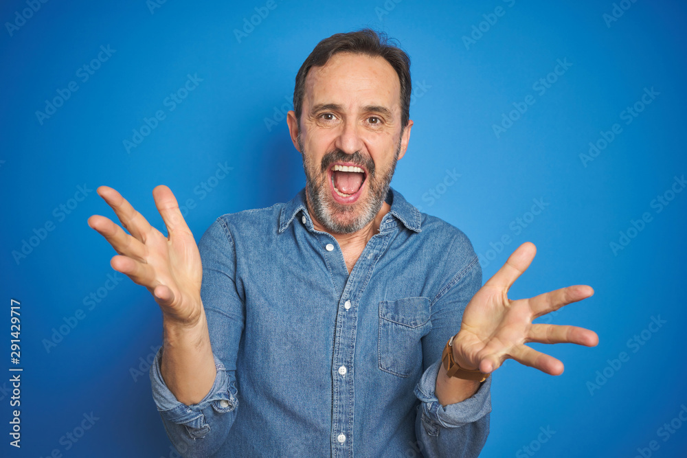 Handsome middle age senior man with grey hair over isolated blue ...