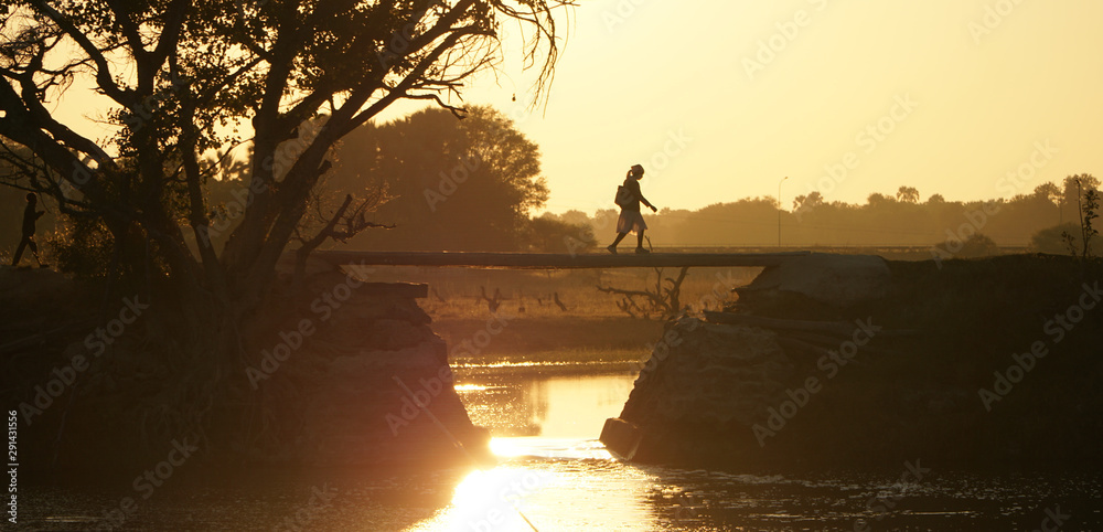 Okavango / Botswana - June 2016: Local crossing a bridge during sunrise ...