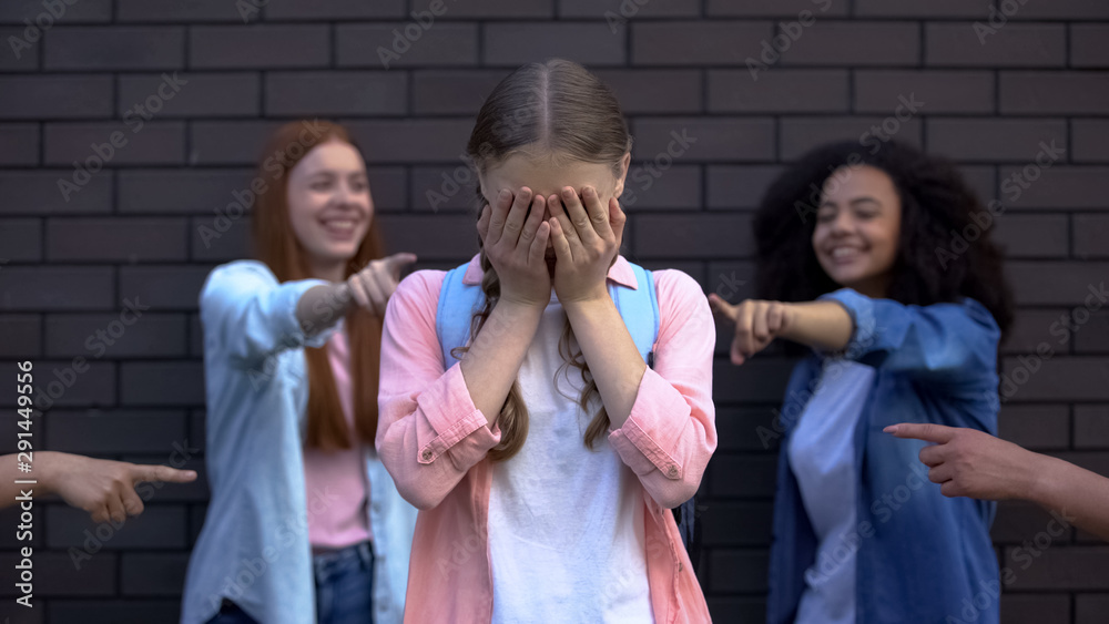 Depressed bullying victim covering face with hands, classmates pointing ...