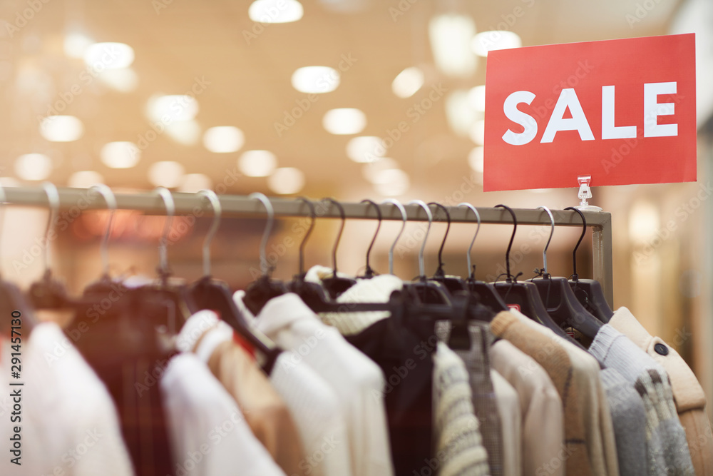 Background image of red SALE sigh on rack with clothes on display in ...