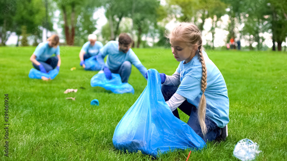 School girl with group of eco volunteers picking up litter park, saving ...