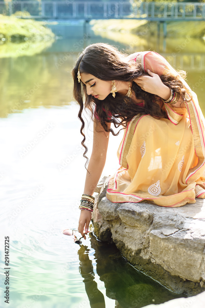 Indian woman sitting near river and gethering water into jug Stock ...