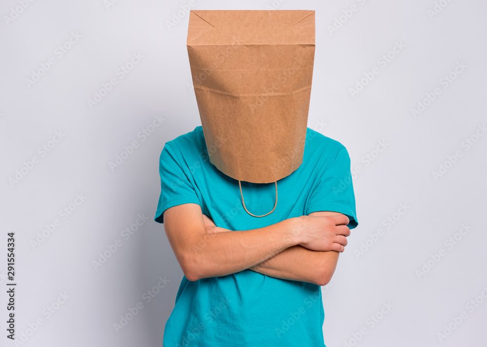 Portrait of offended teen boy with paper bag over head with crossed ...