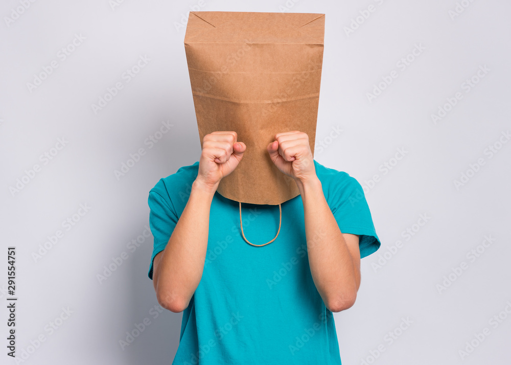 Unhappy teen boy with paper bag over head covering face with hands ...