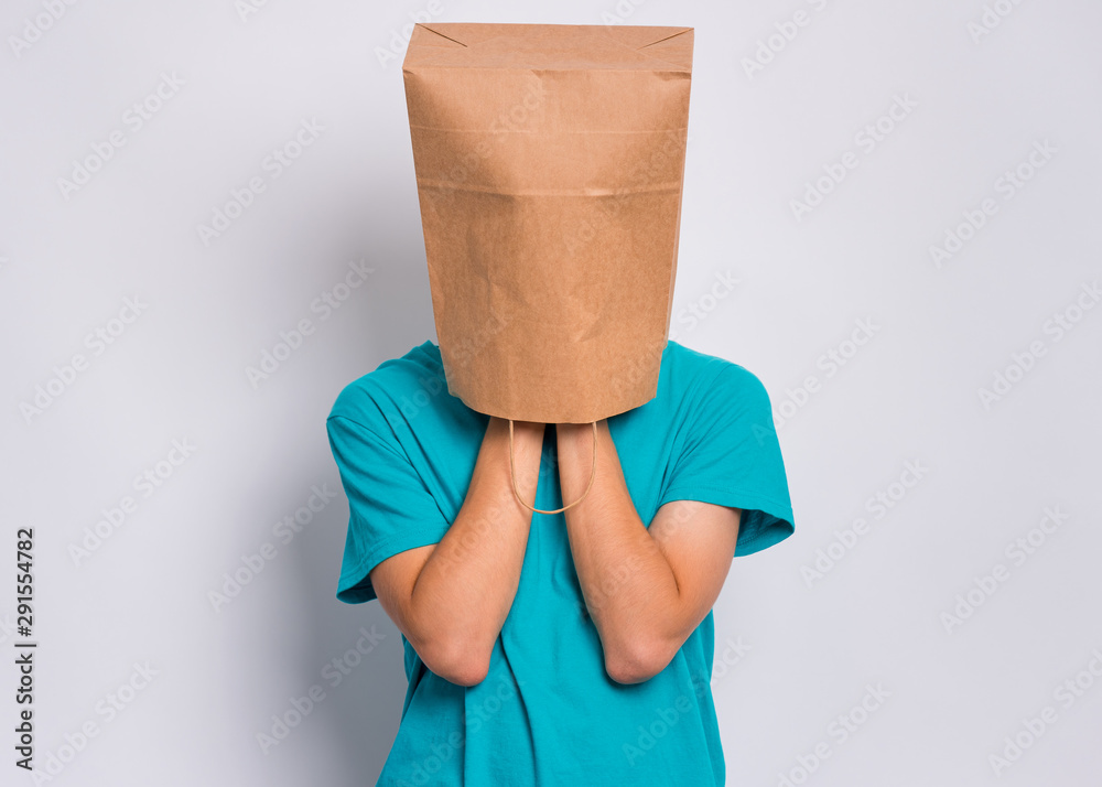 Unhappy teen boy with paper bag over head covering face with hands ...