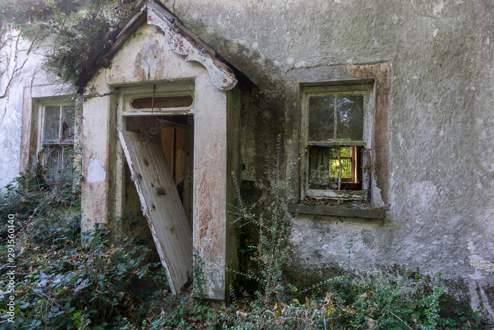 Front of derelict cottage with entrance door leaning to one side in ...