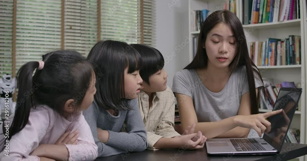 Teacher showing students information on a laptop during a tech lesson ...