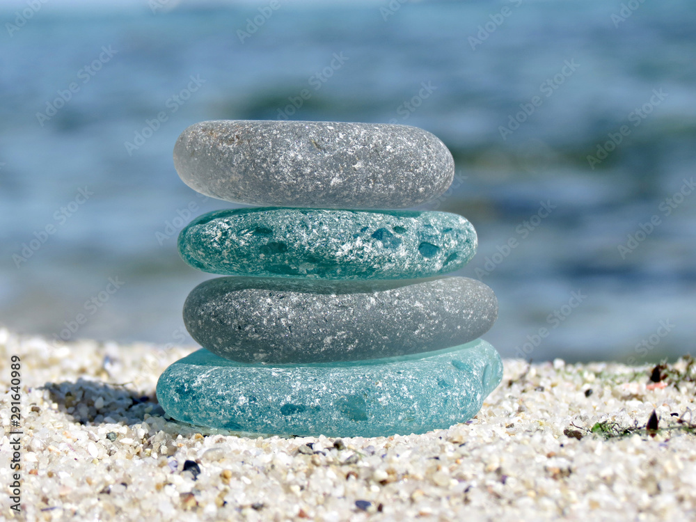 Sea glass pyramid on beach sand with blurred seascape background ...