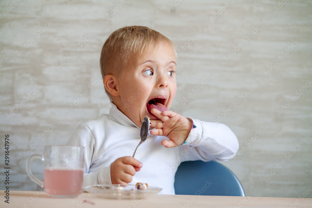 A little boy with a genetic disease Down Syndrome is sitting at the ...