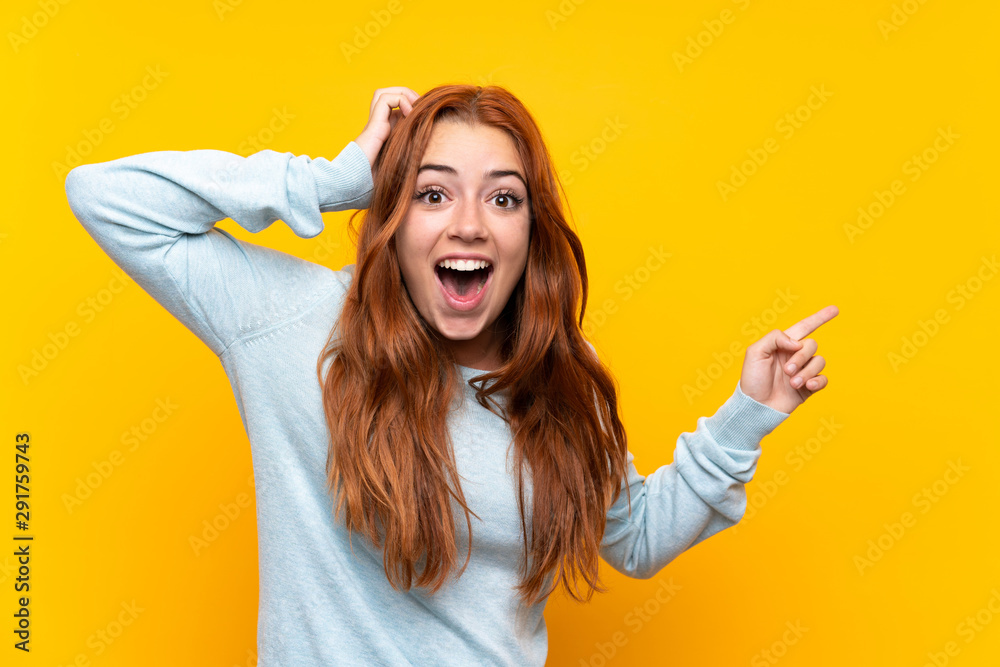 Teenager redhead girl over isolated yellow background surprised and ...