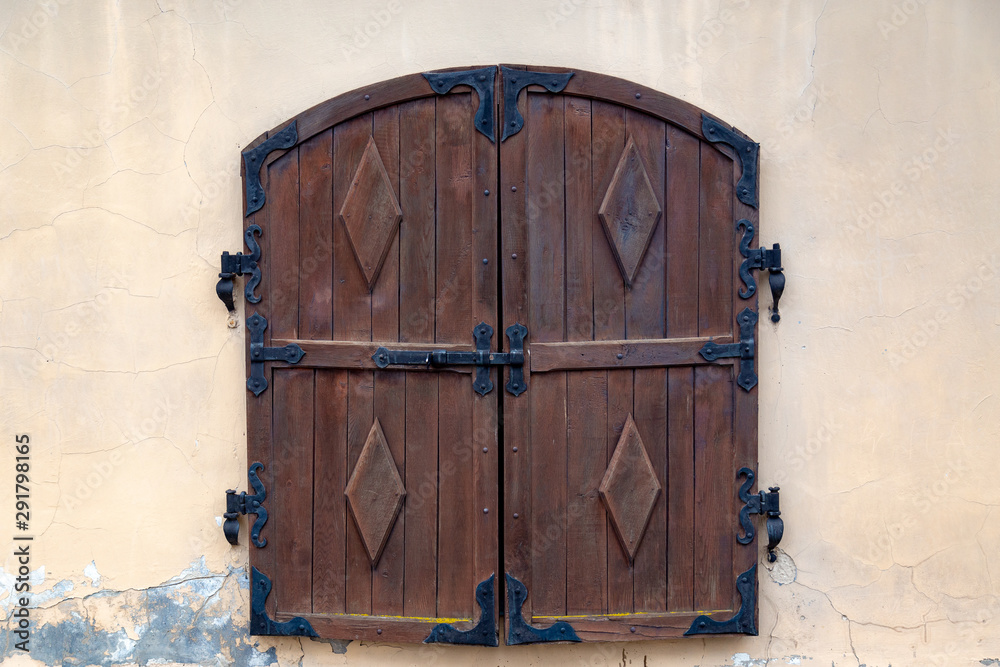 Window protected with wooden shutters made of rustic brown wood and ...