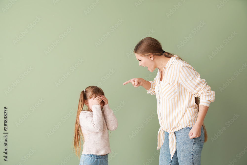 Angry mother scolding her little daughter on color background Stock Photo | Adobe Stock