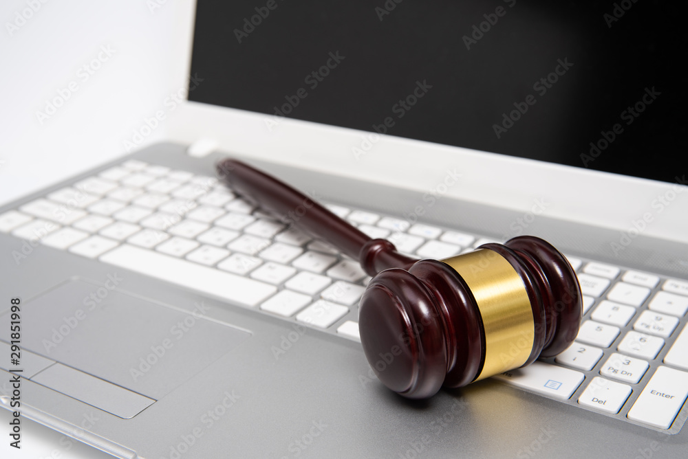 Wooden judge gavel on a silver laptop computer, cyber law or online ...