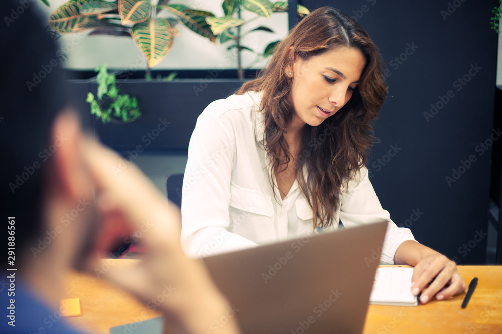 Business woman taking notes in a notepad during her meeting with a ...