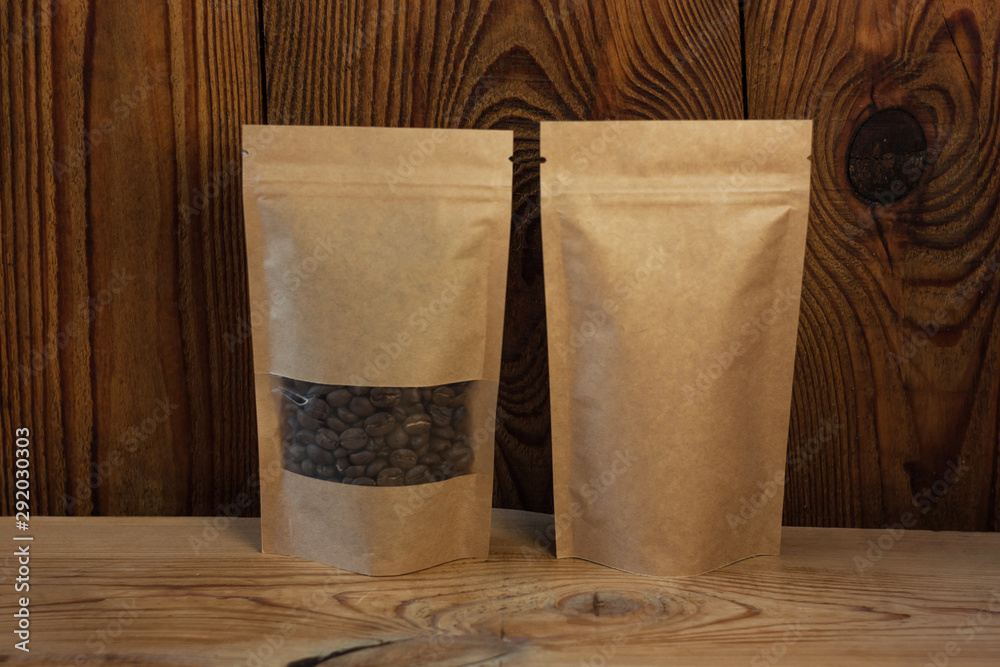 Brown kraft paper pouch bags with coffee beans front view on a wooden ...