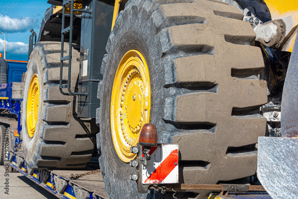wheel of a bulldozer close-up on a transport platform. Concept: road ...