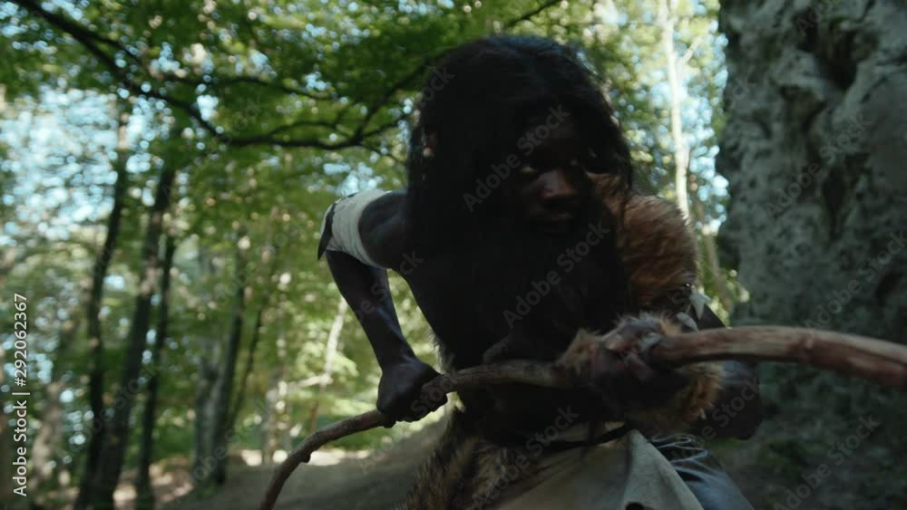 Primitive wild african man in animal fur walking slowly in the woods ...