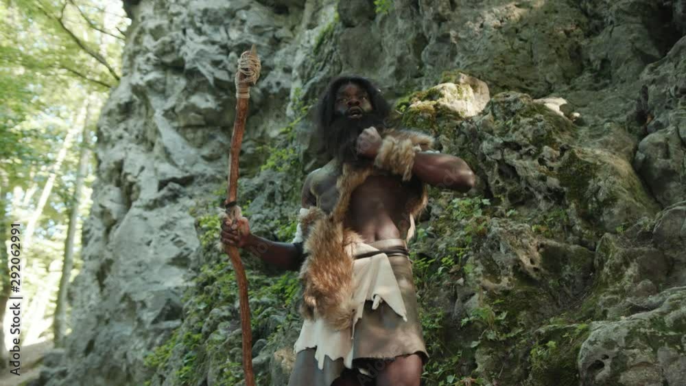 African primitive proud tribe leader in animal fur standing on mountain ...